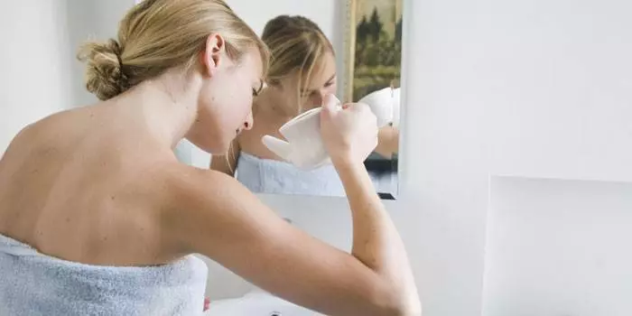 मुलगी स्नानगृहात आपले नाक धुवते