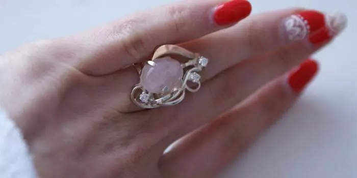 Zlatý prsteň s ružovým kremeňom na ženskej ruke