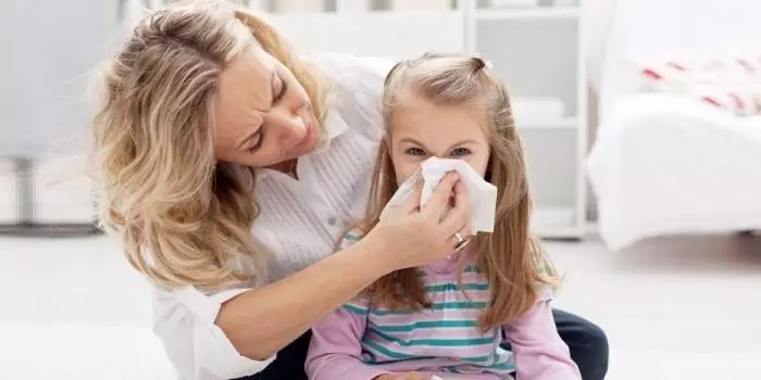 La mamma pulisce il naso della ragazza con un fazzoletto