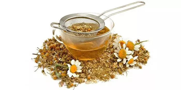 Cangkir ku kaldu chamomile, saringan sareng chamomile garing