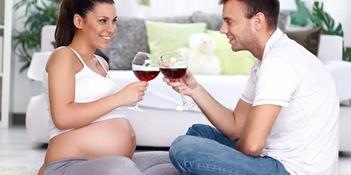 אישה בהריון שותה יין בחברת גבר