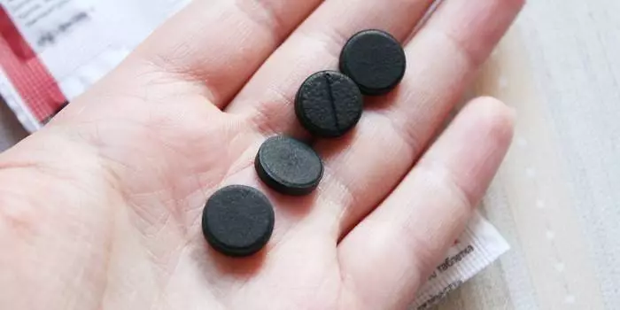 Aktivētās ogles tabletes plaukstā