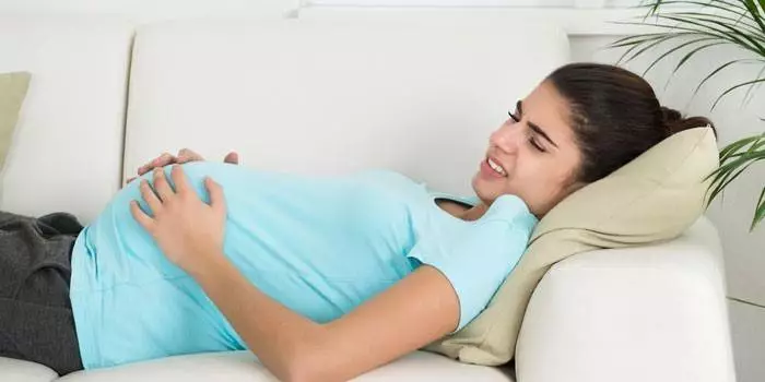 Nėščia mergina guli ant sofos