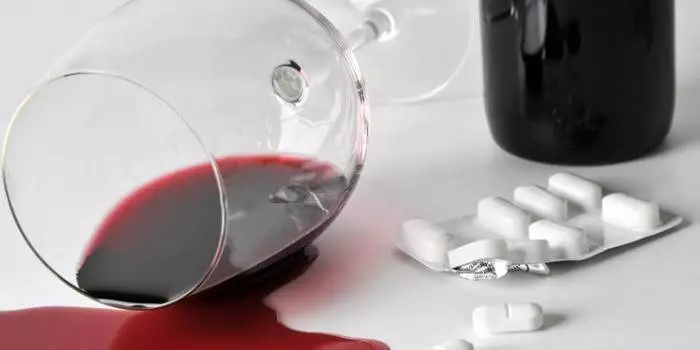 Kaatunut lasillinen viiniä ja pillereitä