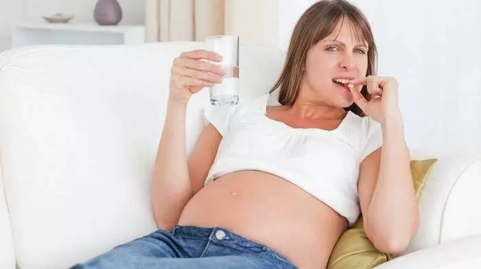 אישה בהריון שותה ויטמינים עם סידן