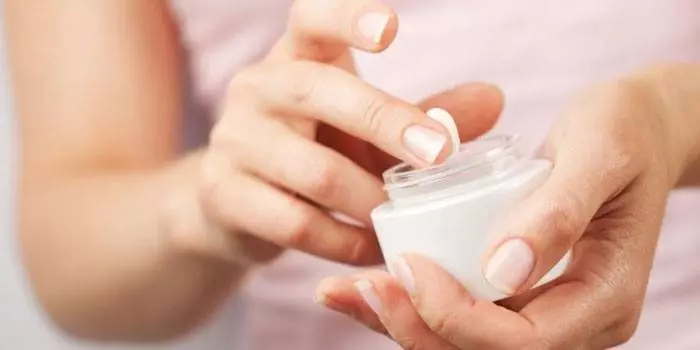 Jar with cream in hands