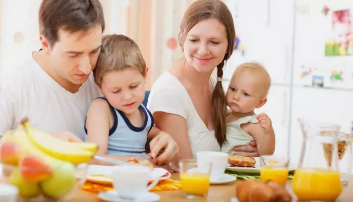 Familio kun infanoj ĉe la tablo