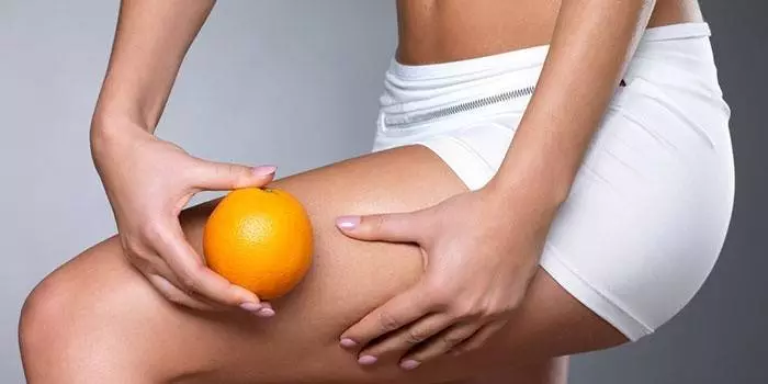 Une fille tenant une orange dans ses mains