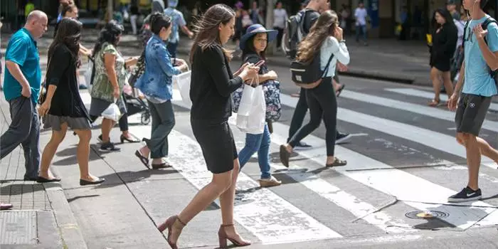 Batang babaye nga adunay telepono sa usa ka crosswalk