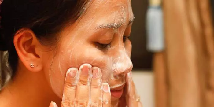 Flickan tvättar ansiktet