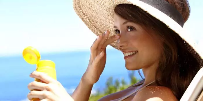 Une fille met de la crème solaire sur son visage